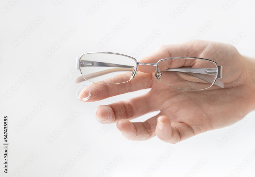 Pair of contact lenses on the index finger of the hand and glasses for ...