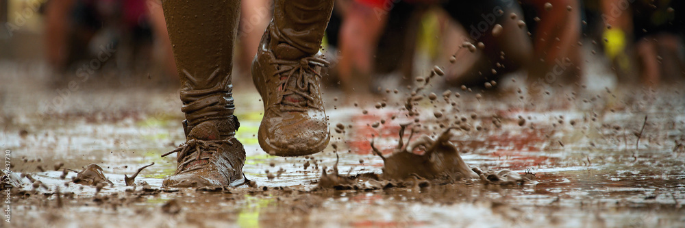 Mud race runners.Crawling,passing under a barbed wire obstacles during ...