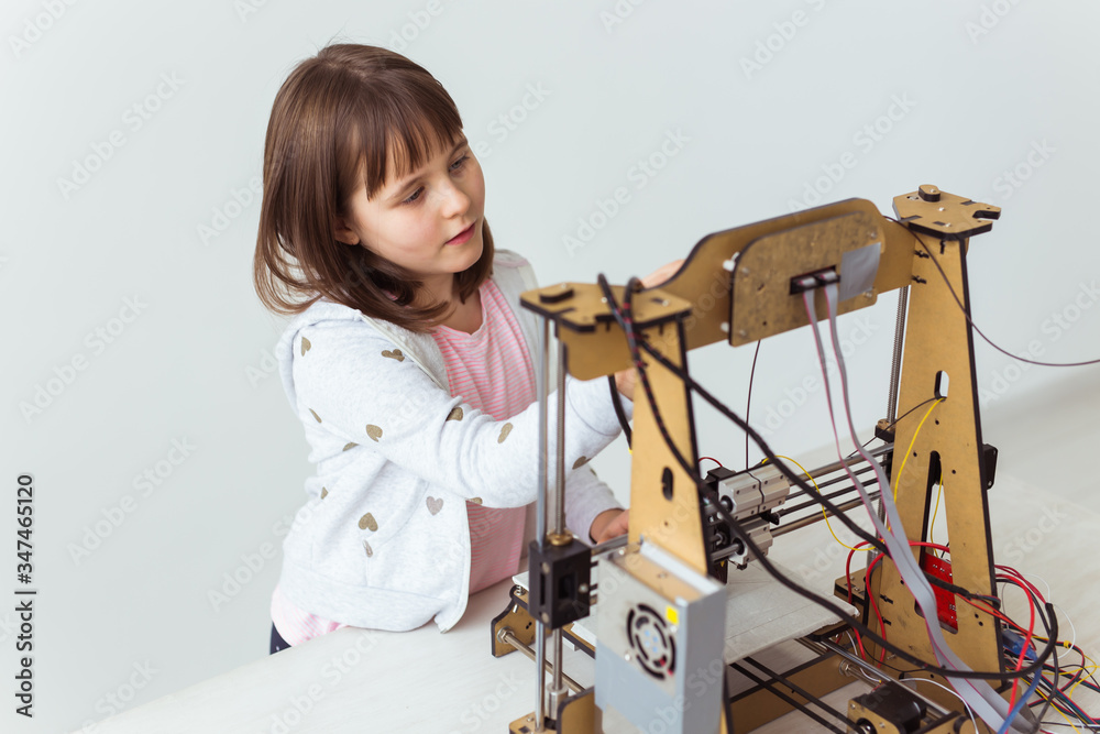 Cute girl with 3d printed shutter shades is watching her 3d printer as ...