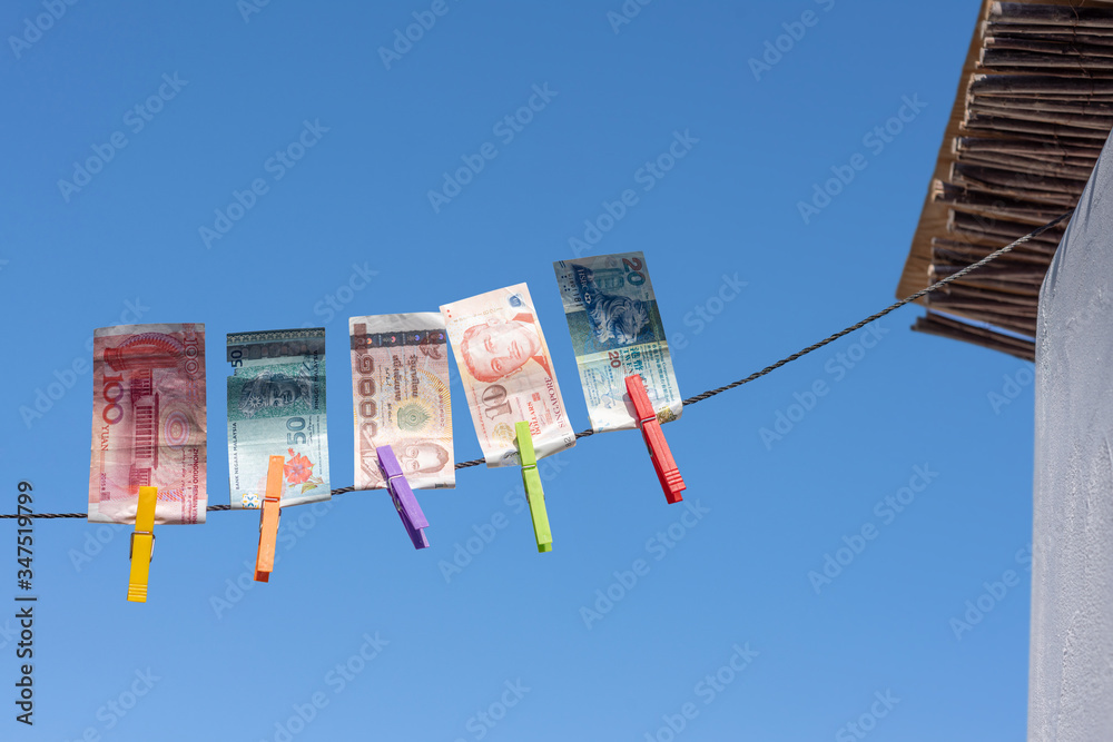 Money of south-east Asia with a clothespin on a rope opposite blue sky ...