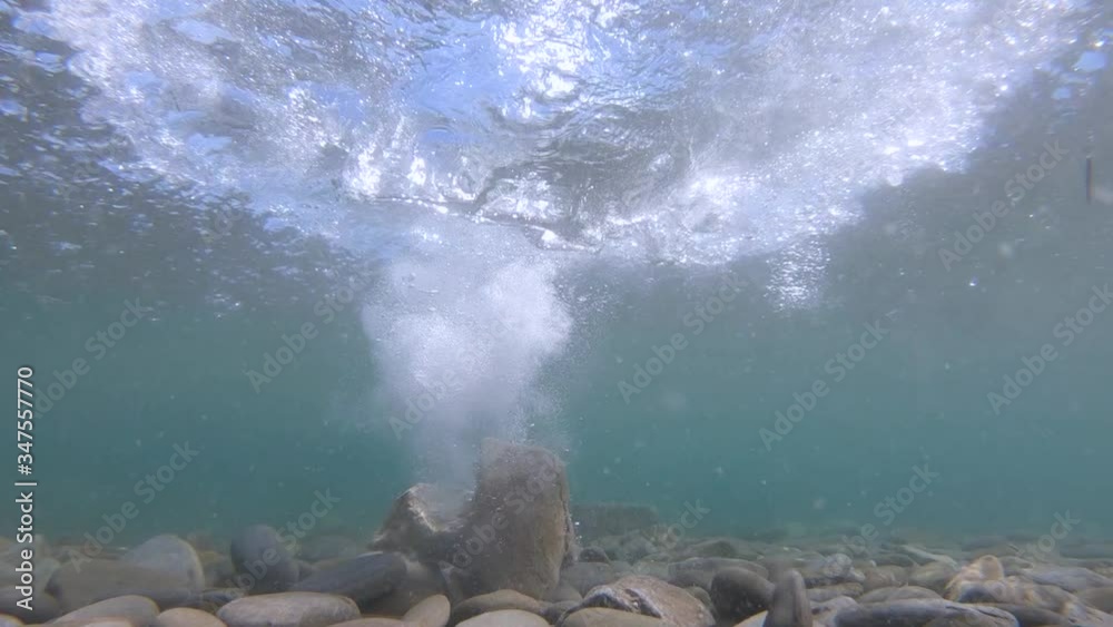 Slow motion underwater view of sea bottom. Rocks falling in water ...