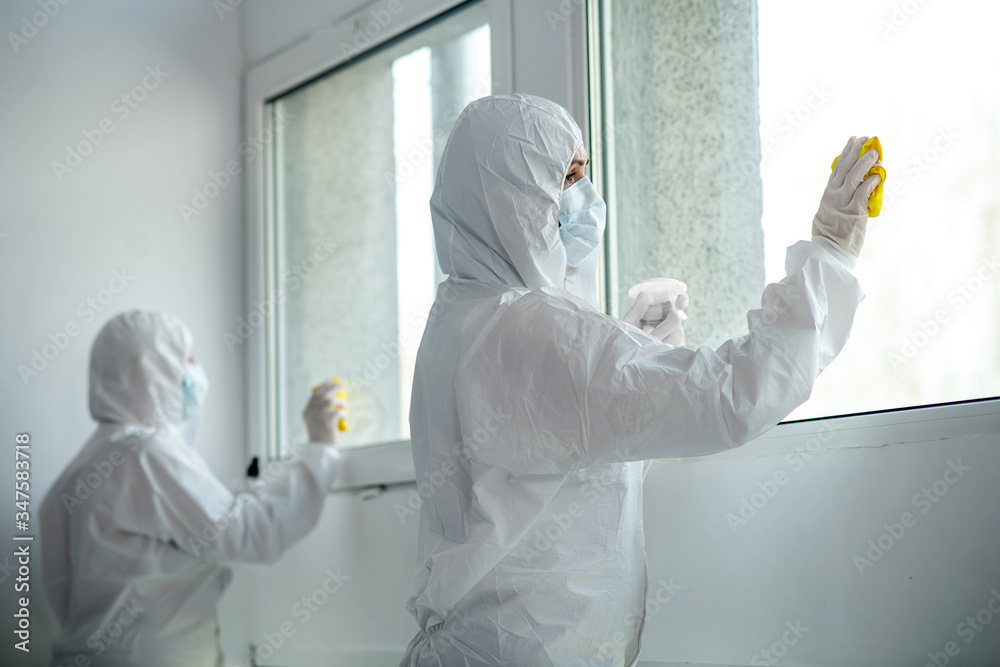 Medical workers in protective clothing and medical masks disinfecting ...