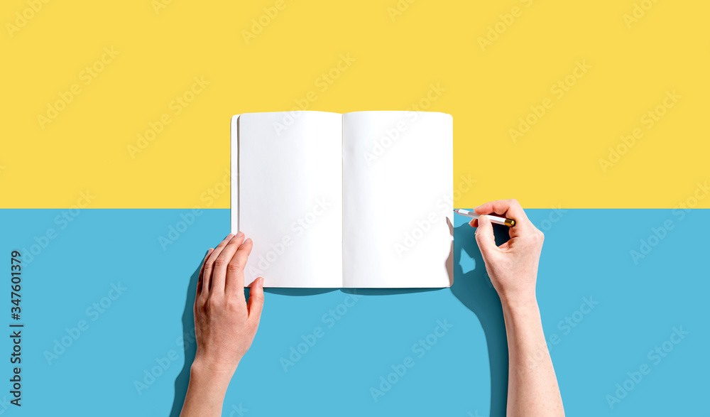 Person writing in a notebook from above Stock Photo | Adobe Stock