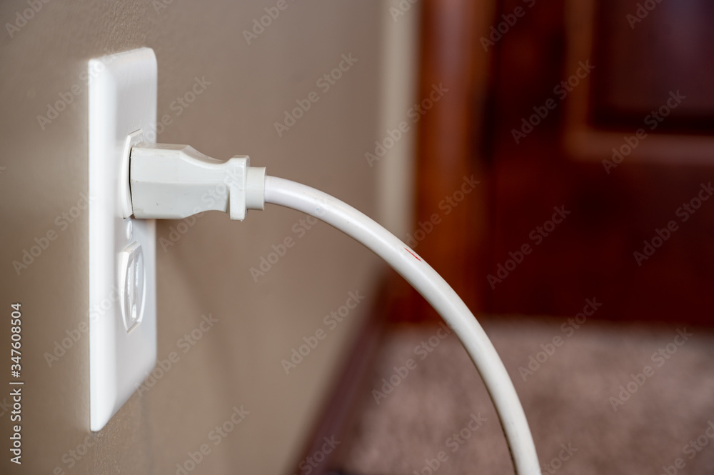 Side view of white power cord plugged into a white wall outlet Stock ...