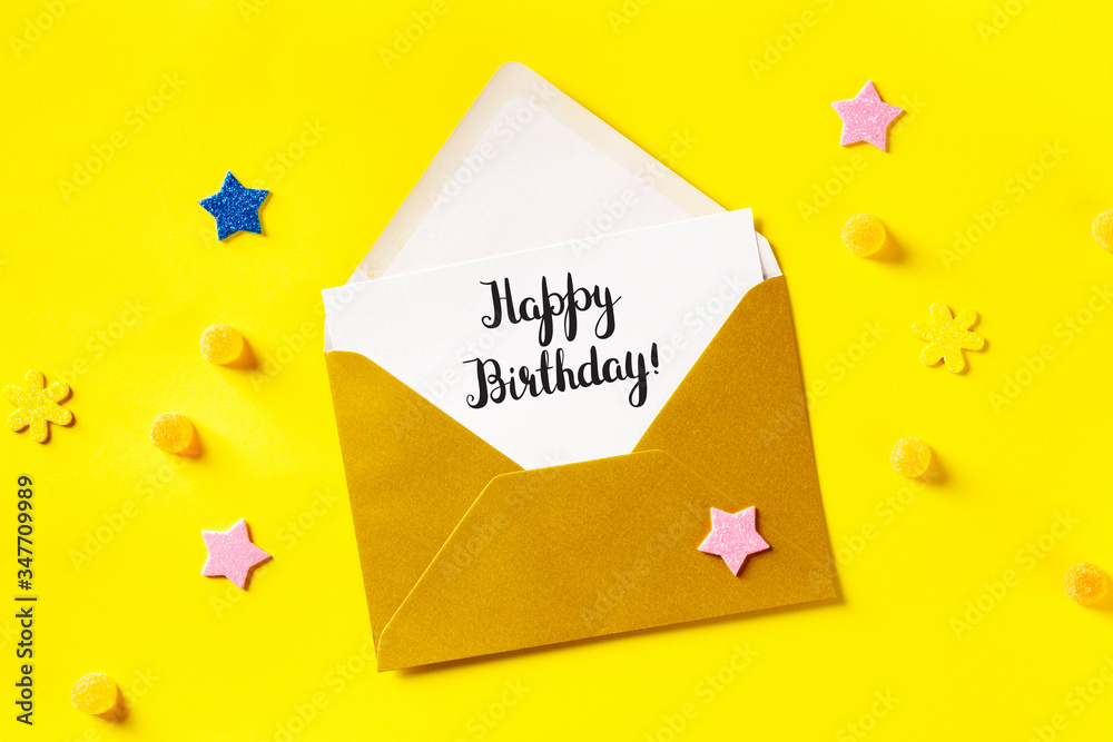 Happy Birthday card in a golden envelope, shot from above on a yellow ...