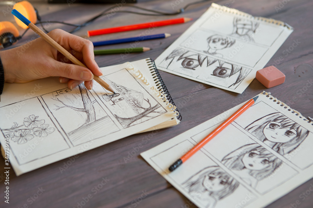 Artist drawing an anime comic book in a studio. Wooden desk, natural ...