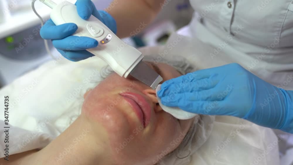 Beautician makes skin cleansing procedure for a young woman. Apply a ...
