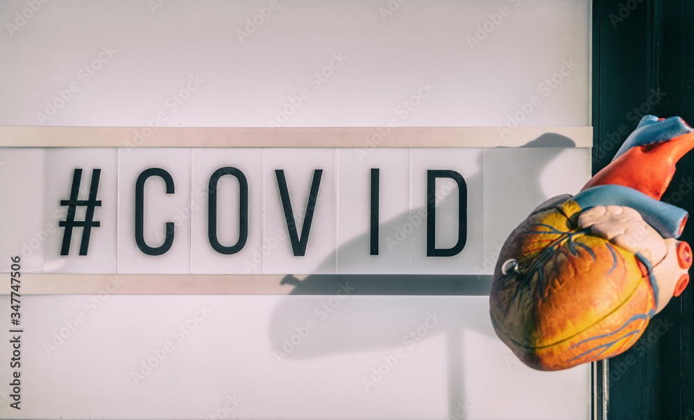COVID-19 hashtag sign next to medical heart model showing ...