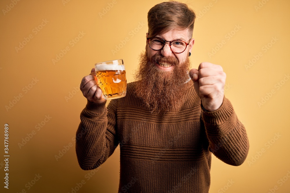 Irish redhead man with beard drinking a glass of refreshing beer over ...