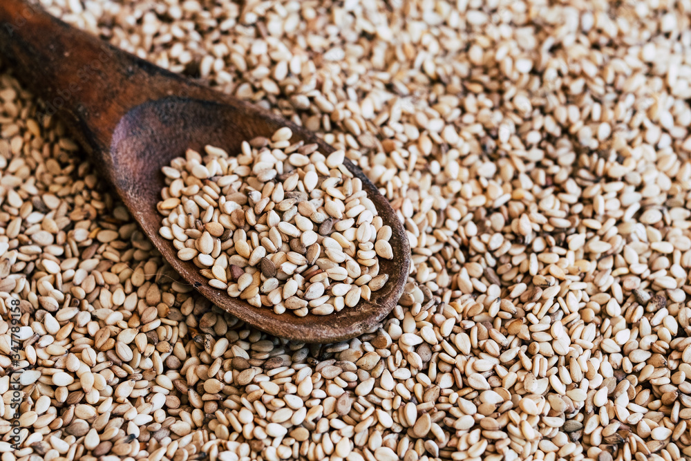 Graines de sésame dans une cuillère en bois et arrière plan graines de ...