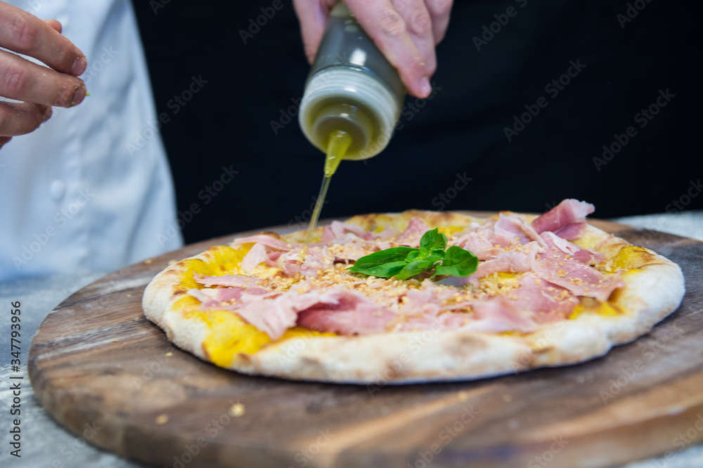 detail of the hands of a pizza maker who works for the various stages ...