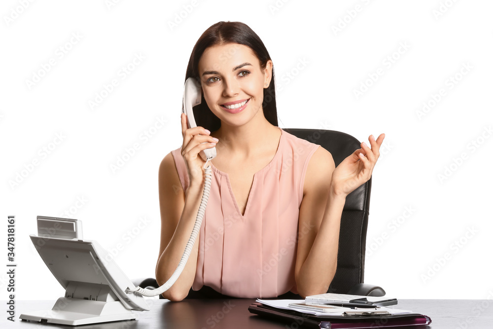 Beautiful young secretary talking by telephone at table on white ...