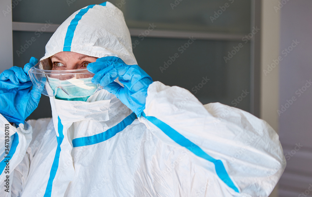 Doctor or nurse in protective clothing with safety glasses in clinic ...