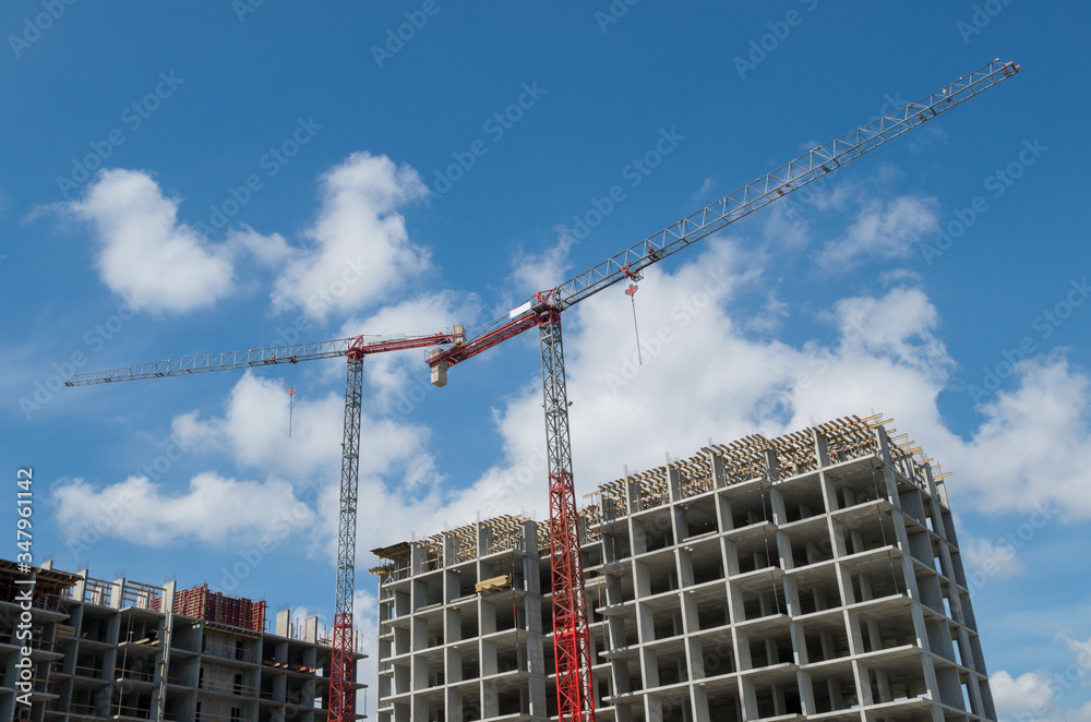 Red tower cranes standing on construction site unfurling their jibs ...