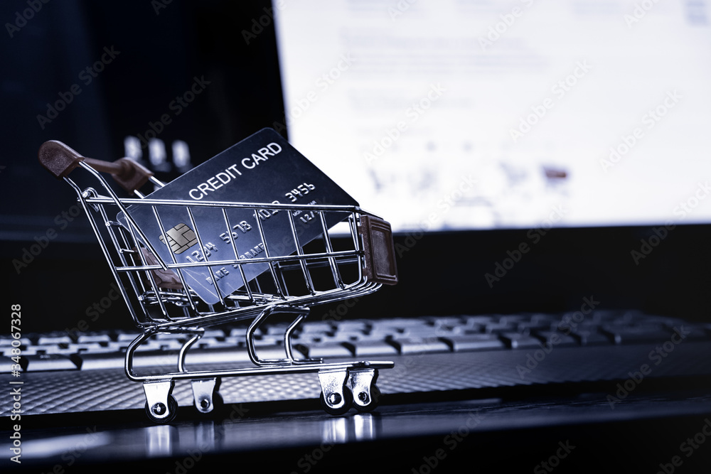 close up Shallow focus Credit Card in mini shopping card with Computer ...