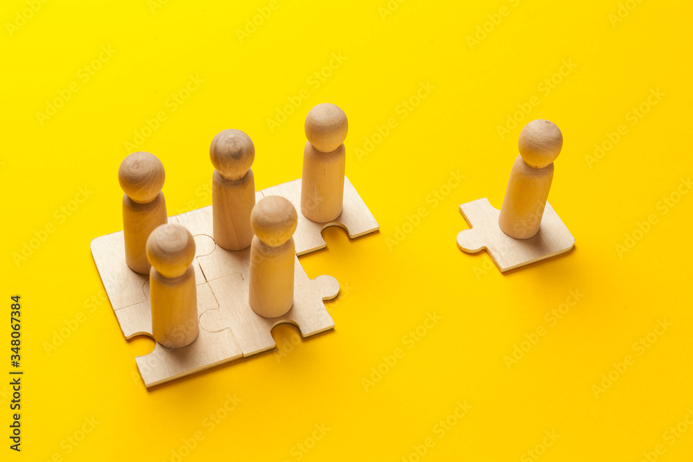 Wooden figures on puzzles on yellow background as a symbol of team ...
