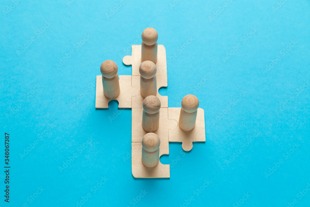 Wooden figures on puzzles on blue background as a symbol of team ...