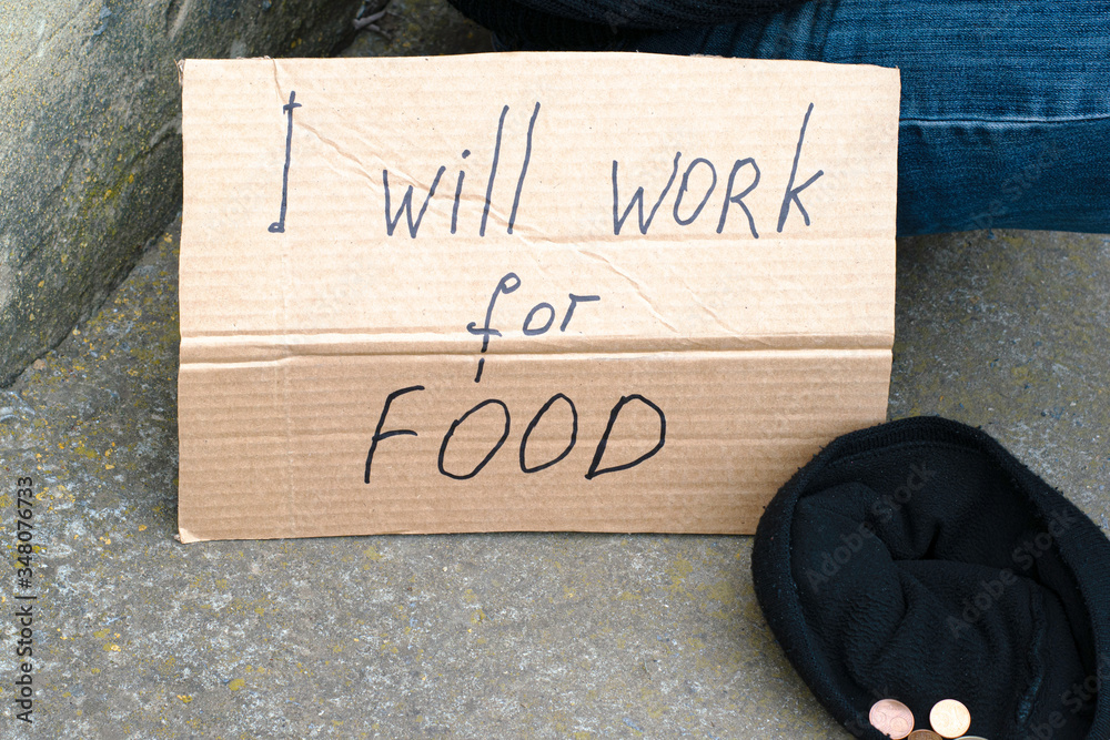 unemployed man sitting on the ground holding the cardboard sign saying ...