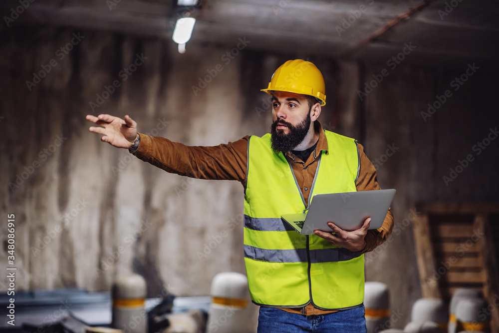Foto de Young bossy handsome bearded supervisor standing inside of ...