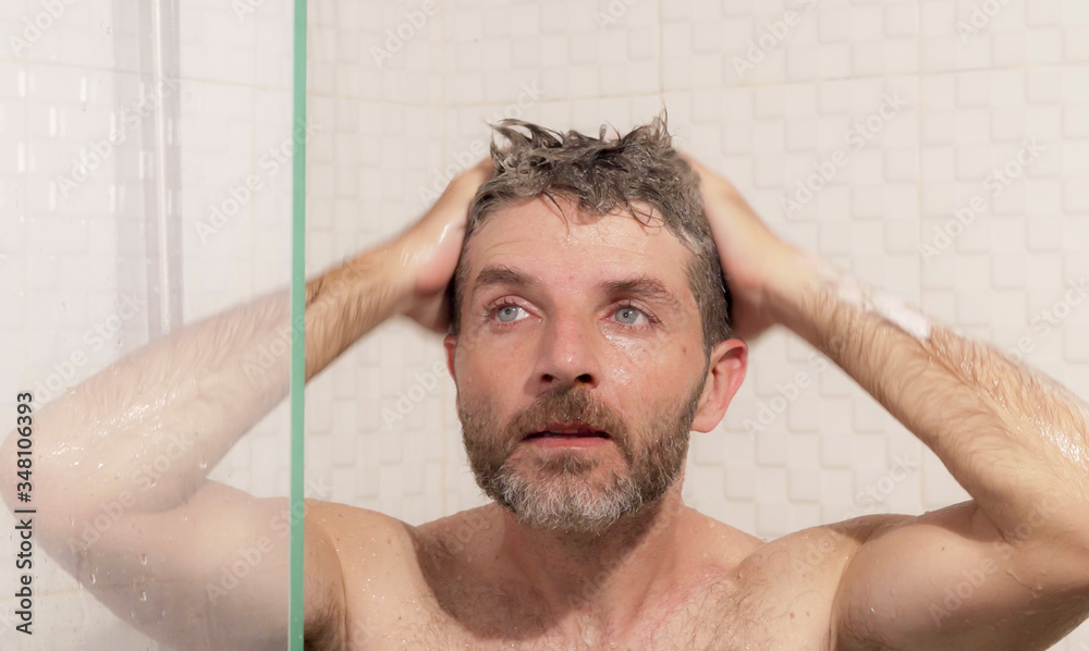 young attractive and happy man with beard taking a shower at home ...