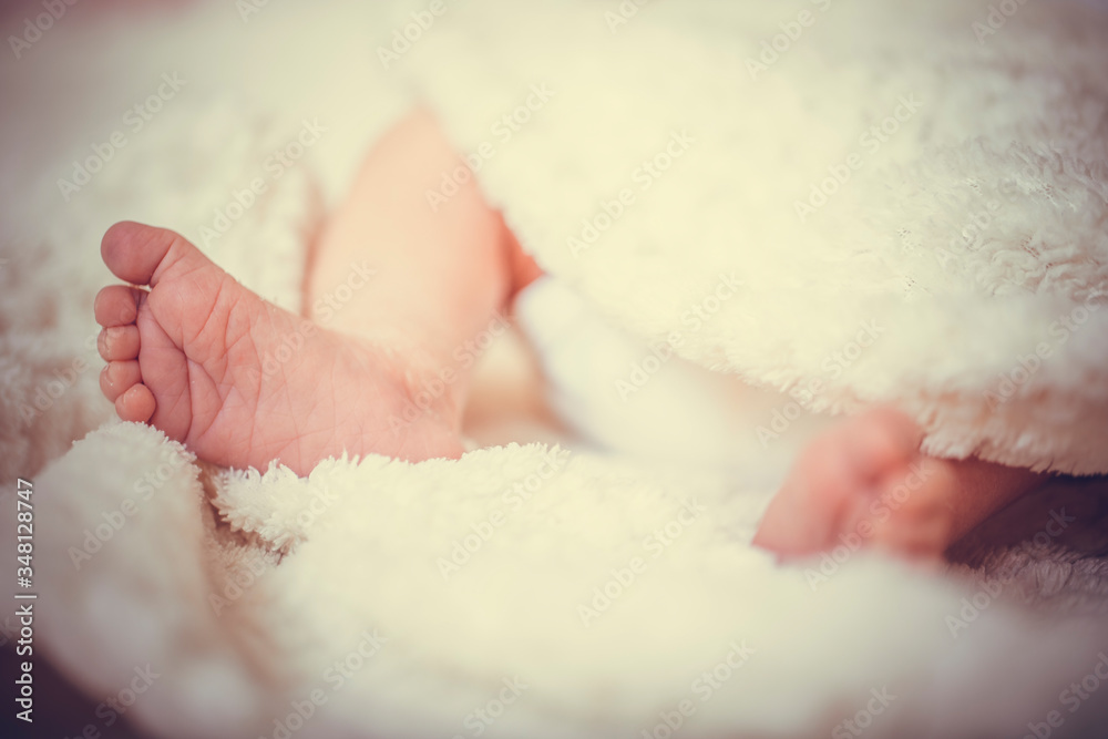 Newborn feet. Sweet baby in a gentle morning light on the bed. Bare ...