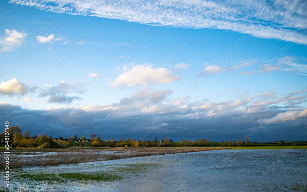 Rural landscape with dramatic cloudy sky, farm land floded by local ...