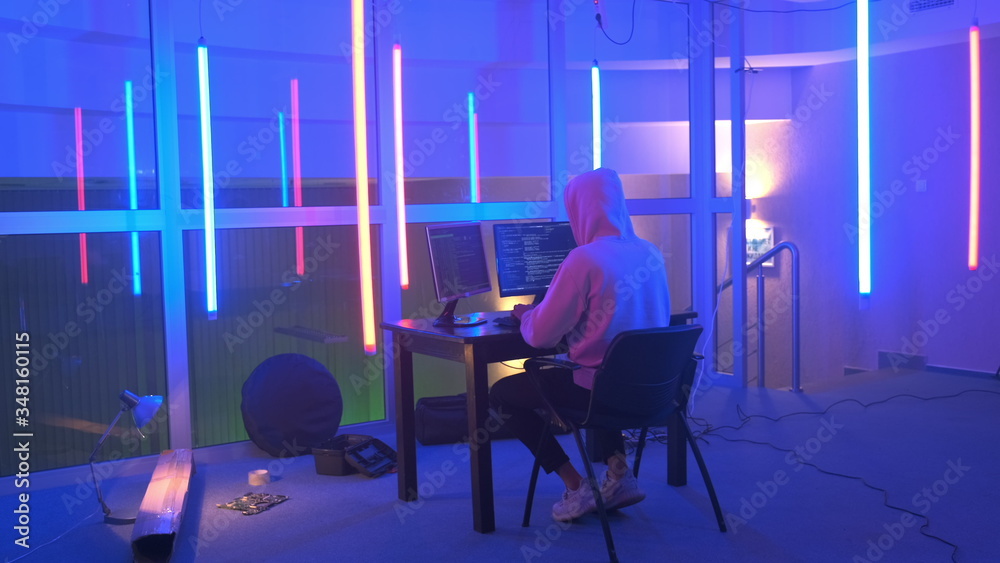 Hacker working place: hacker working in a room with colored neon lights ...