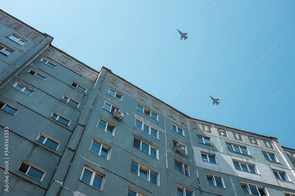 Two military planes flying overhead and over a house in the blue sky ...