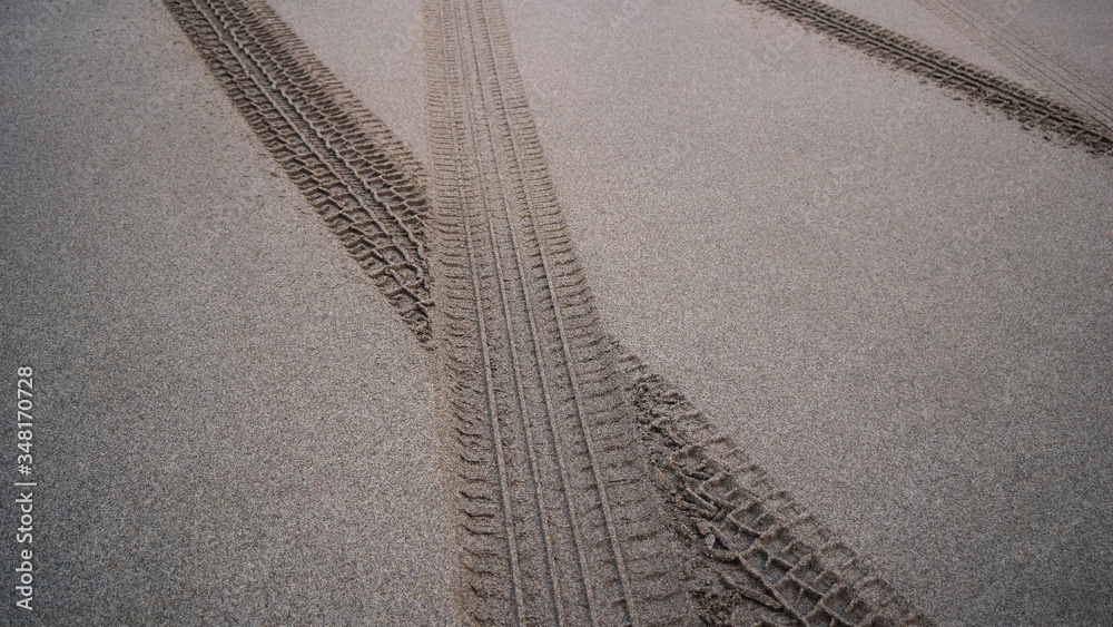 Tire prints on beach sand left by off-road vehicle. Abstract background ...