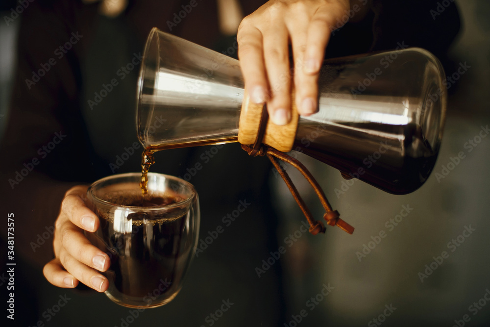 Person pouring fresh aromatic coffee from glass flask in cup, hands ...