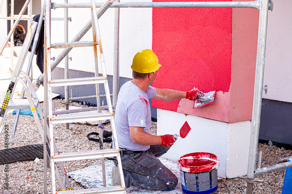 Construction workers plaster the facade of the house. Application Of ...