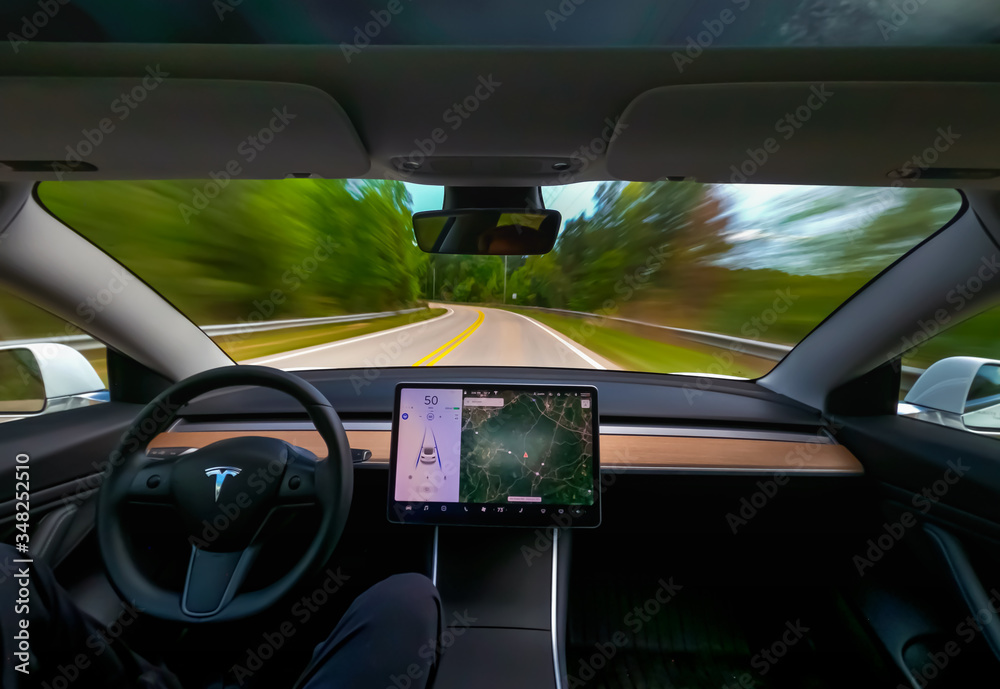 Person driving a new Tesla Model 3 on autopilot Stock Photo | Adobe Stock