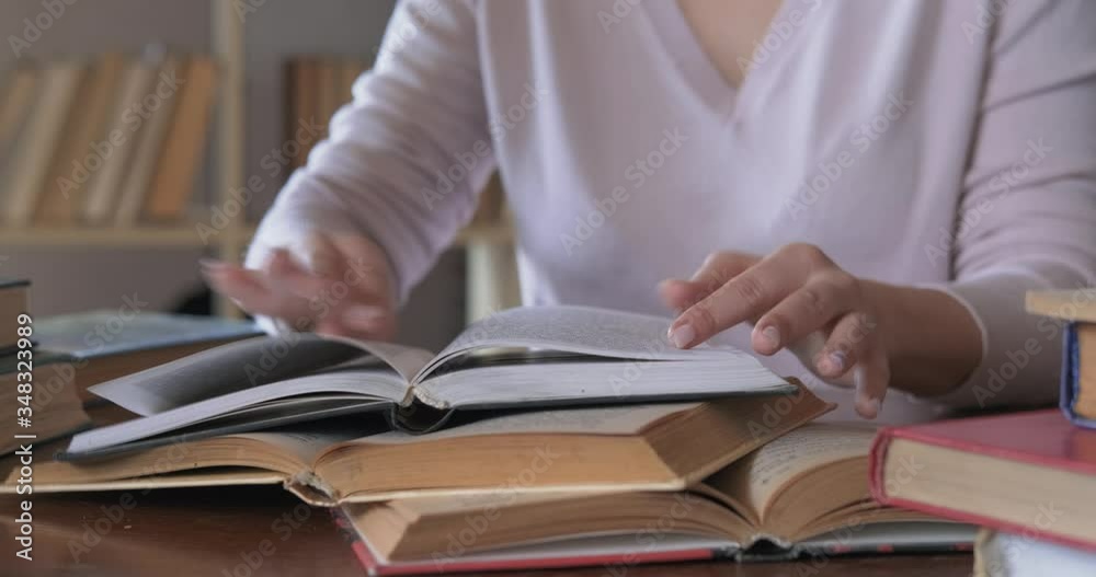 Close-up of open books, lying on table in library, girl sitting at her ...