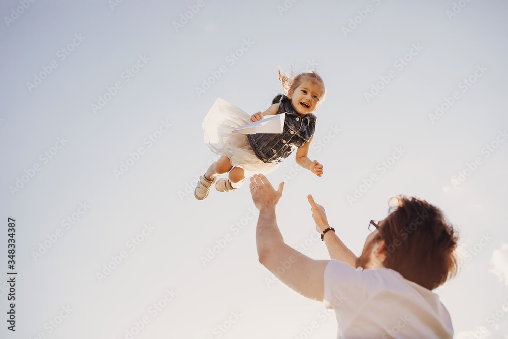 Dad playing with his daughter outdoors. Father throwing up and catching ...
