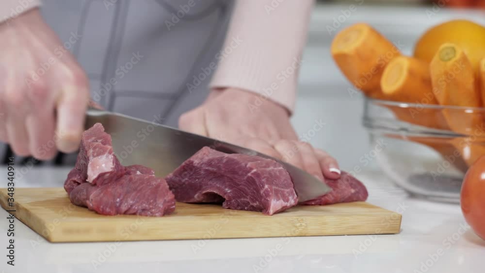 Woman cutting raw meat on small pieces with kitchen knife cutting board ...