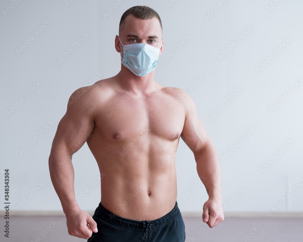Male bodybuilder in a medical mask with muscular bare chest. The guy ...