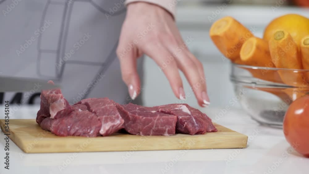 Woman cutting raw meat on small pieces with kitchen knife cutting board ...
