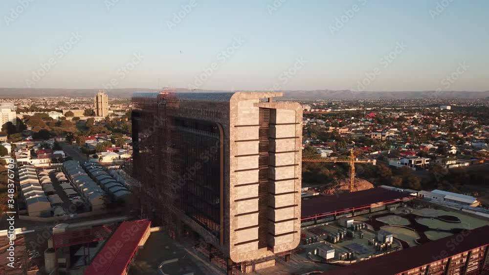 4K aerial drone summer sunrise video of Windhoek red brick large office building in city center ...