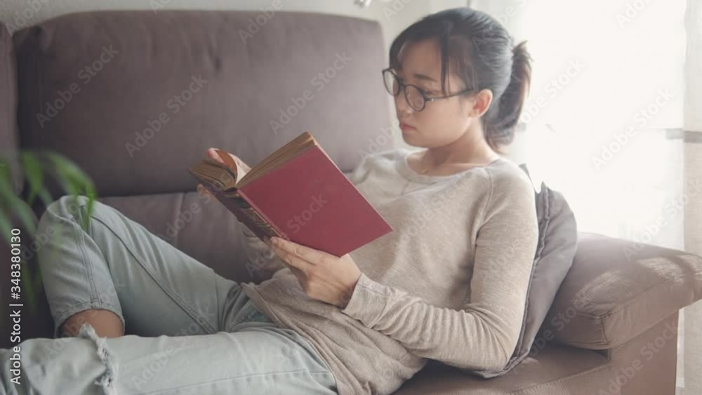Young Asian woman having alone quiet time reading at home. Girl on the ...