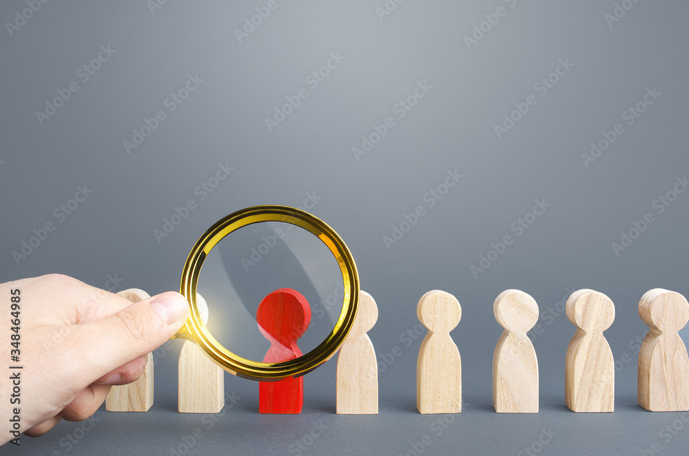 Men with a magnifying glass studies a red person in a people row ...