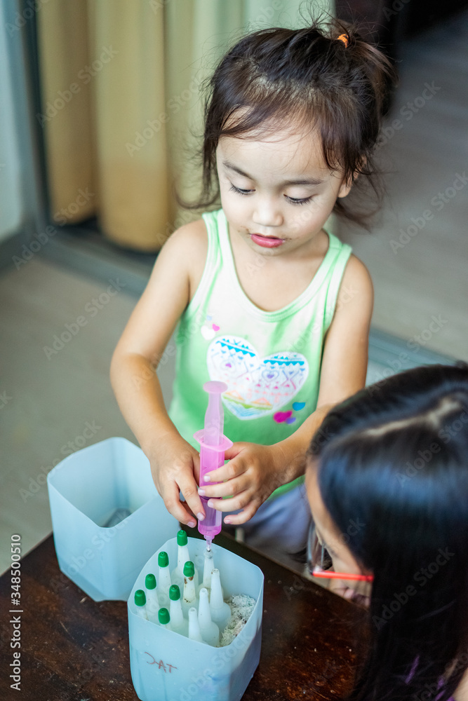 Child injecting organic fertilizer into small containers to be placed ...