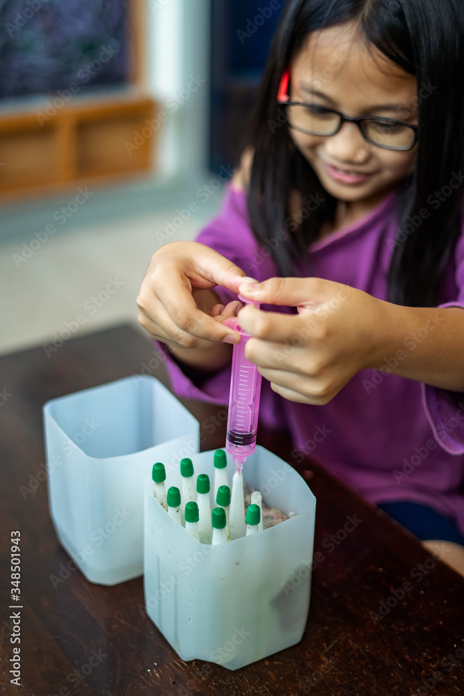 Child injecting organic fertilizer into small containers to be placed ...
