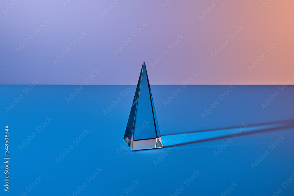 crystal transparent pyramid with light reflection on blue background ...