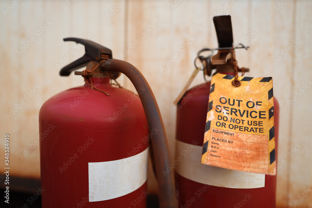 Safe workplaces yellow out of service tag placing on red fire ...