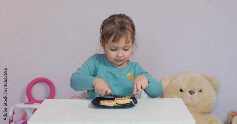 Video Stock Cute little girl child with bright eyes eats curd fritters ...