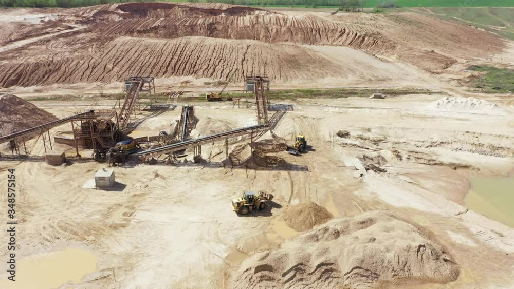 Aerial: work process at sand extraction quarry. Wheel loaders moving ...