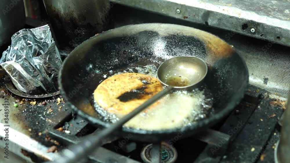 Indian bread paranthas being deep fried in hot oil. Street food in ...