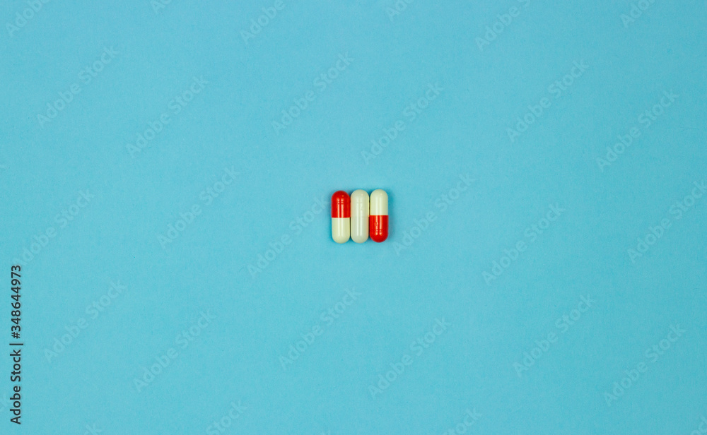 One white and two white-red capsules on a blue background. Three ...