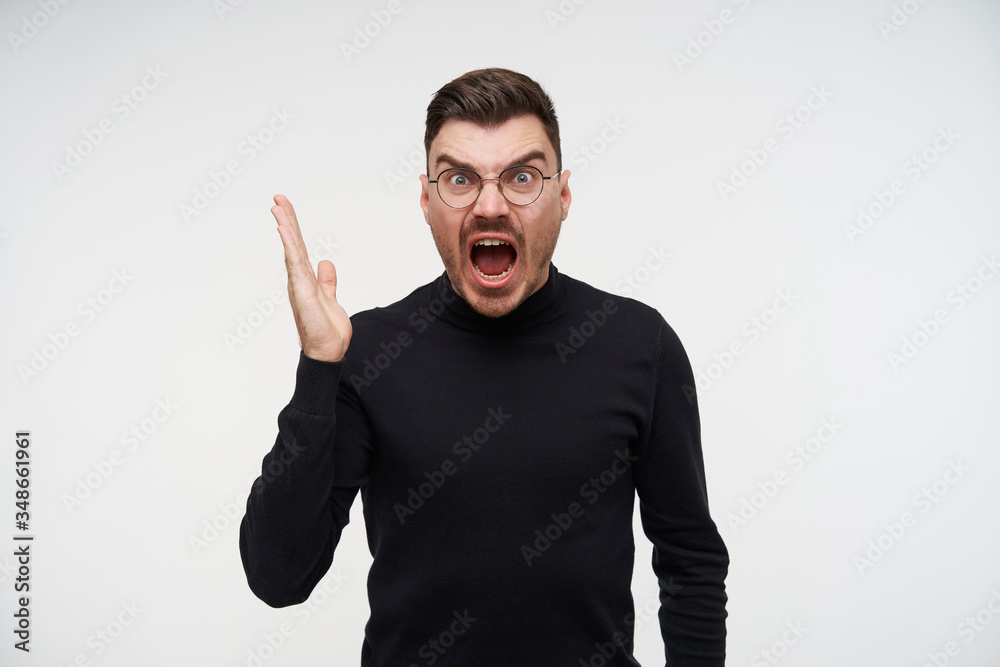 Disgruntled young unshaved brunette man with short haircut screaming ...