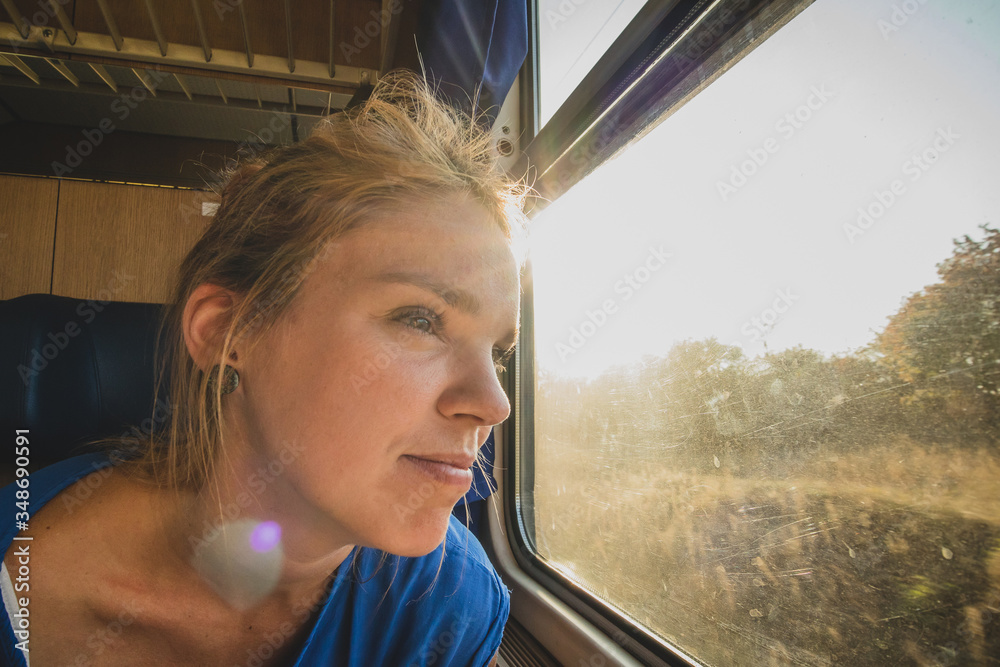 Caucasian woman using looking through a window of an older train with ...